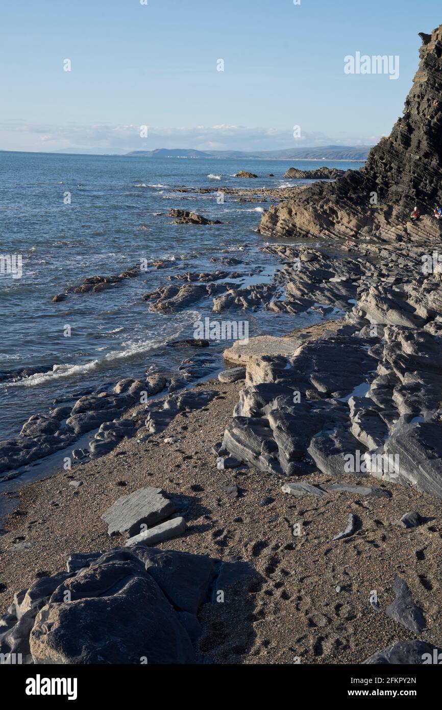 Beach with pebbles,rocks and stacked limestone strata in Ceredigion ...
