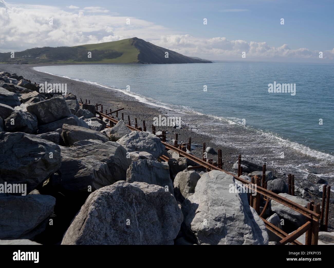 Beach with pebbles,rocks and stacked limestone strata in Ceredigion ...