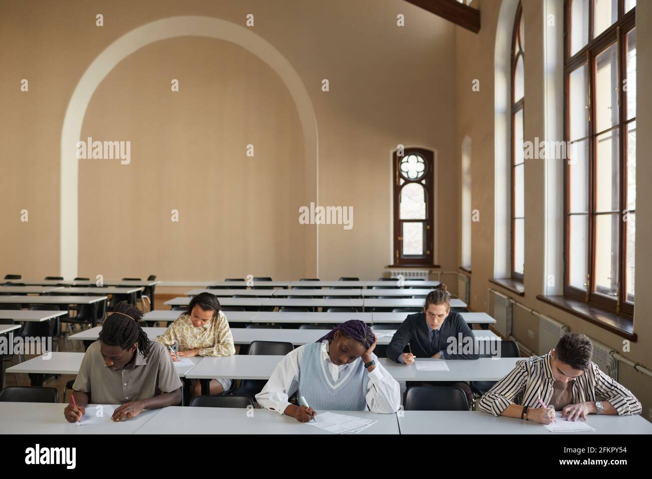Wide angle view at diverse group of students taking exam while sitting ...