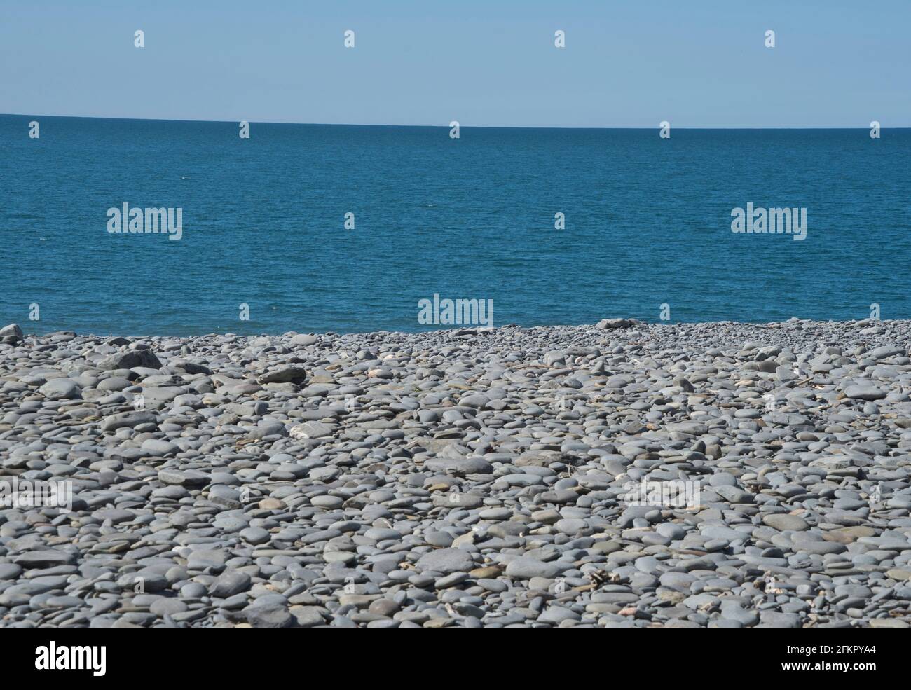 Beach with pebbles,rocks and stacked limestone strata in Ceredigion ...