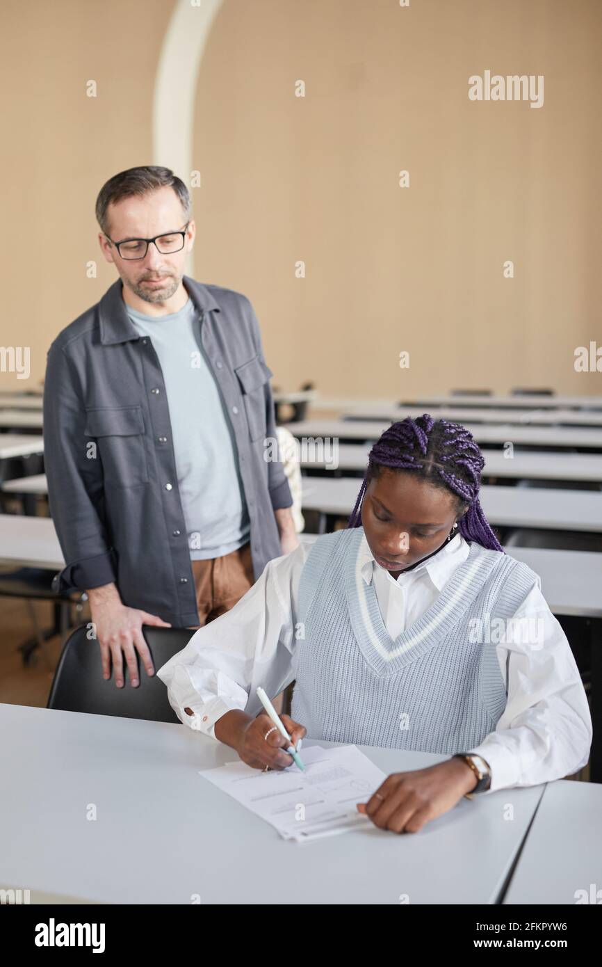 Vertical portrait of young African-American woman taking exam in ...