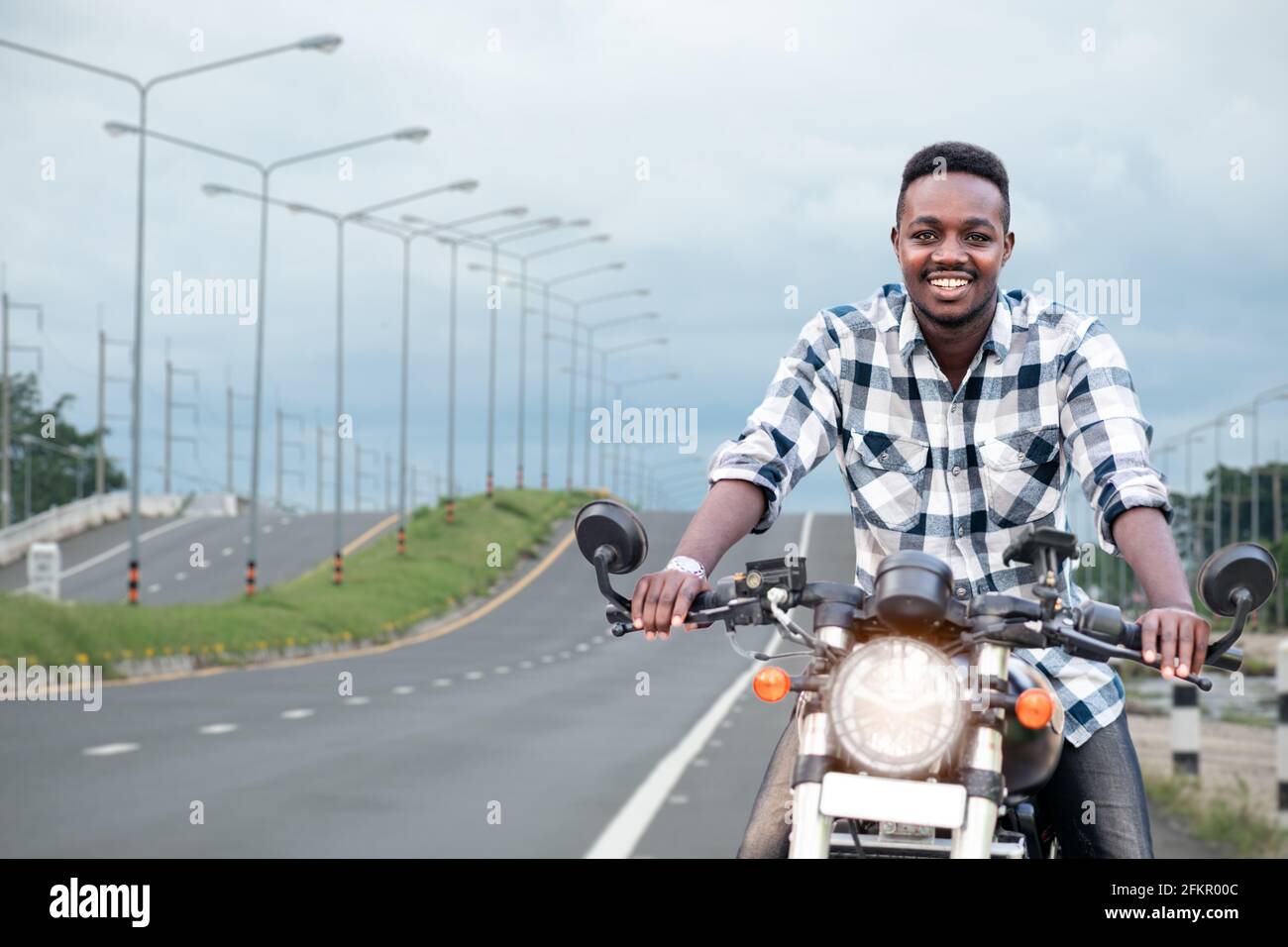 African biker man riding a motorcycle rides on highway road Stock Photo ...