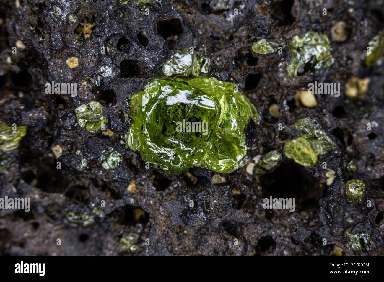 Closup of raw Peridot gemstone, attached to original volcanic host rock ...