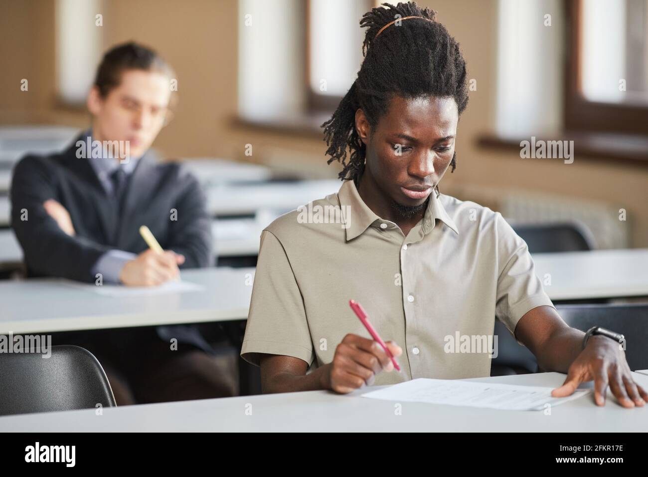 Portrait of young African-American man taking exam in school while ...
