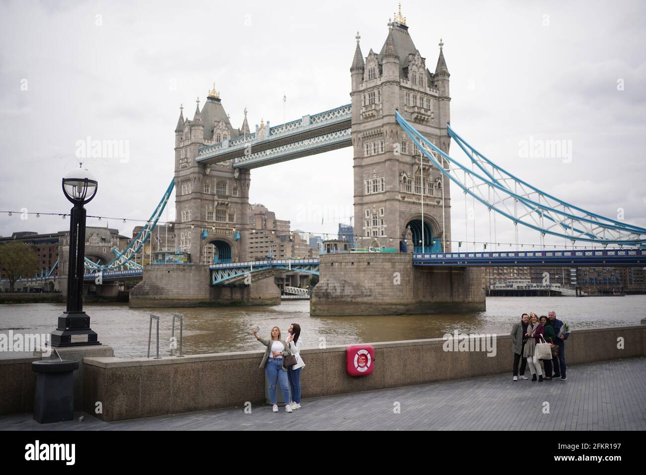 Two women take a photograph next to Tower Bridge in London as heavy ...