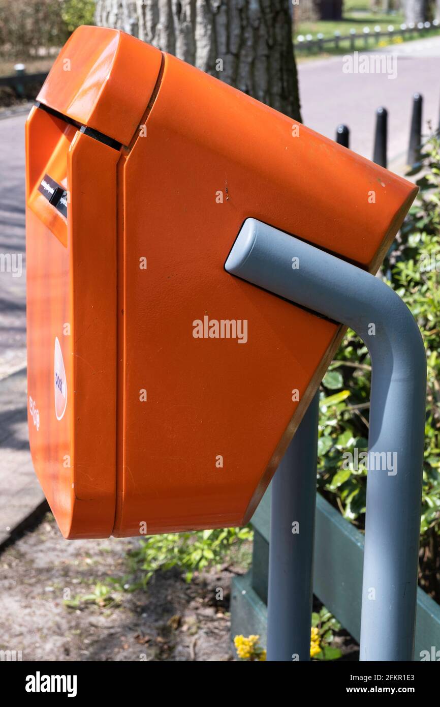 Typical Dutch orange letterbox with PostNL logo, which is outside in a ...