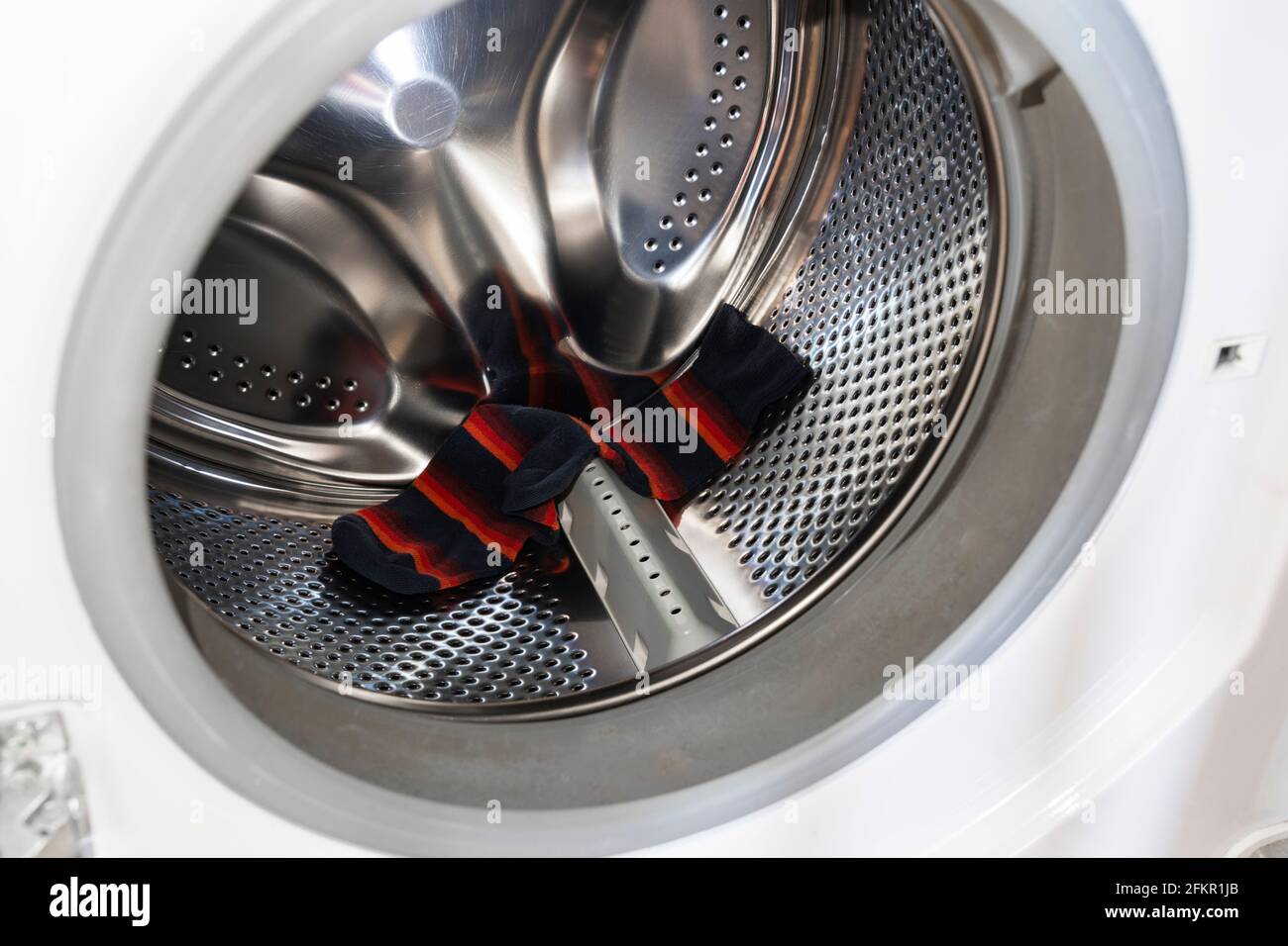 A single red striped sock in a washing machine laundry drum. Concept ...