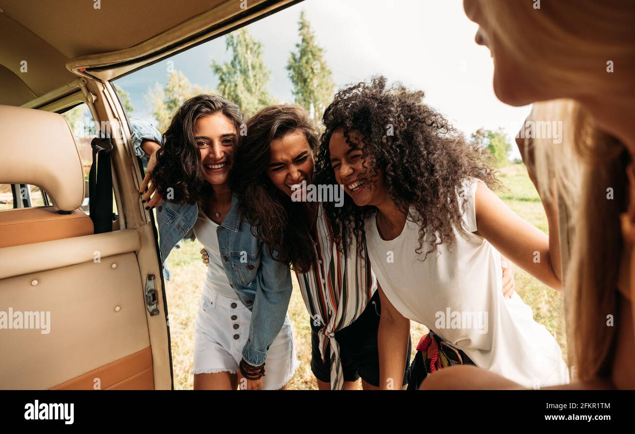 Group of friends on road trip laughing at van. Young people standing ...
