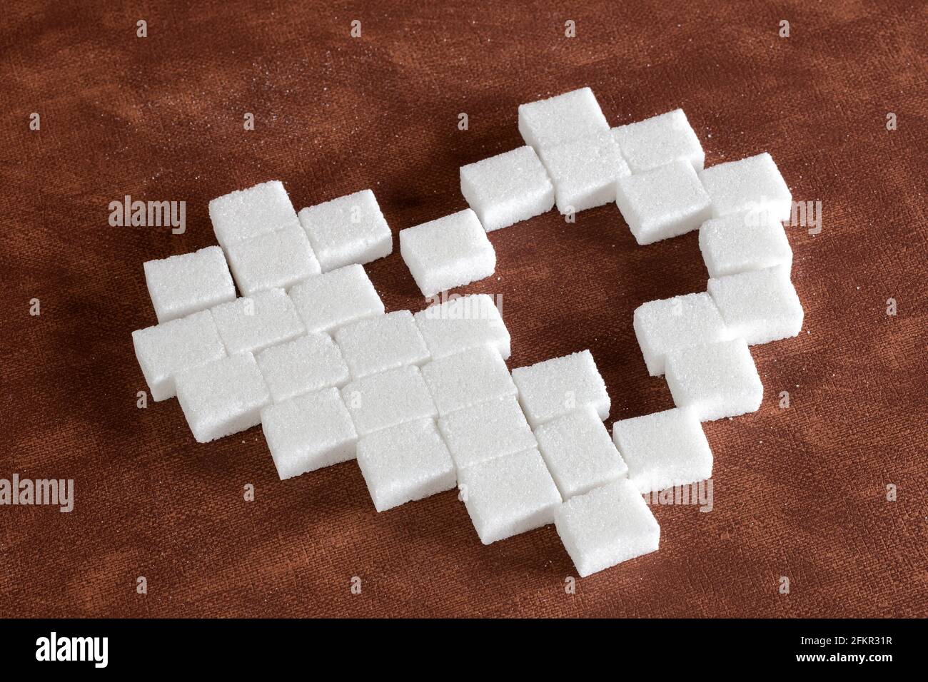 Sweet cute heart made of sugar cubes on brown natural background ...