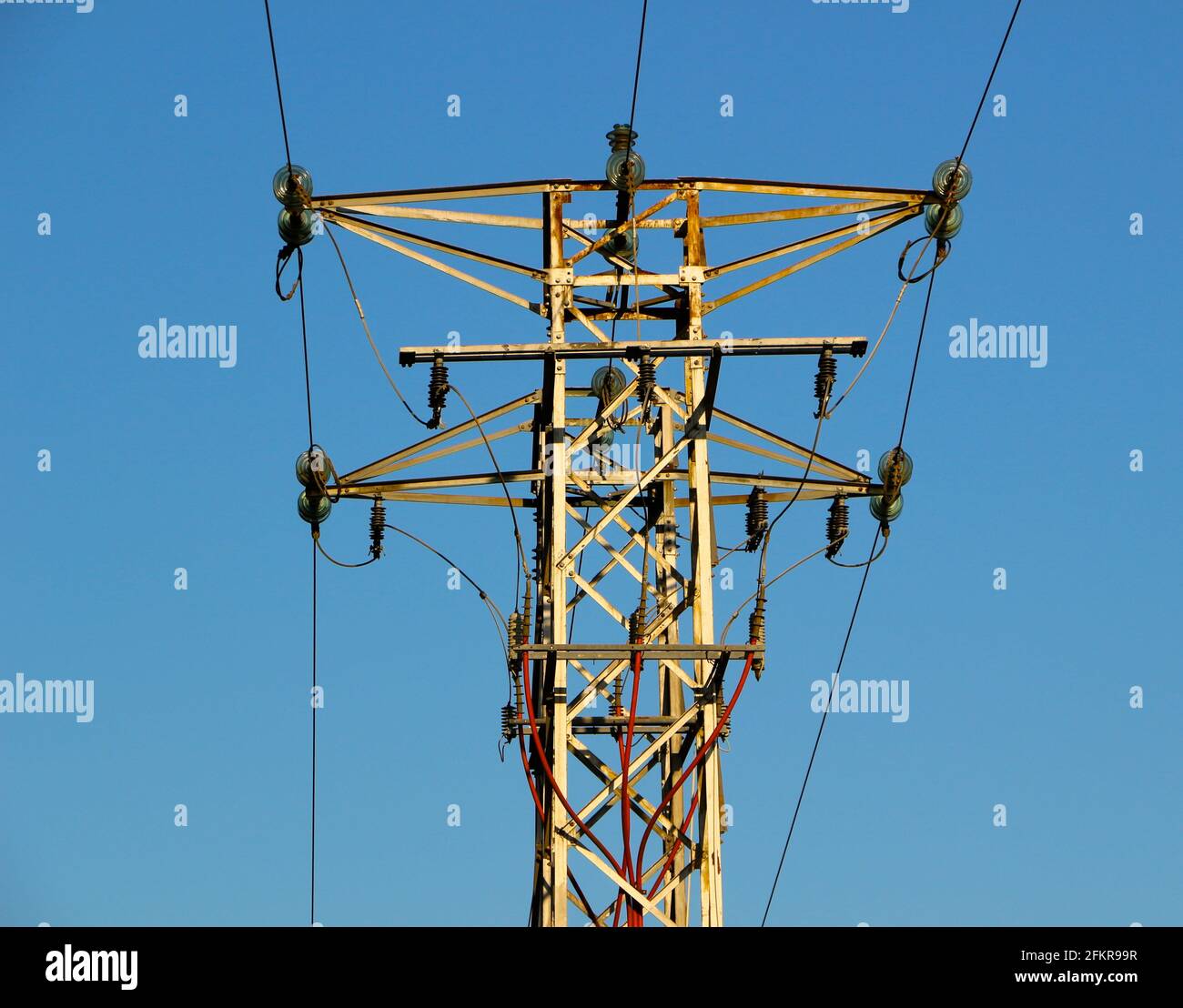 Electricity pylon with overhead cables in sunshine against a blue sky ...