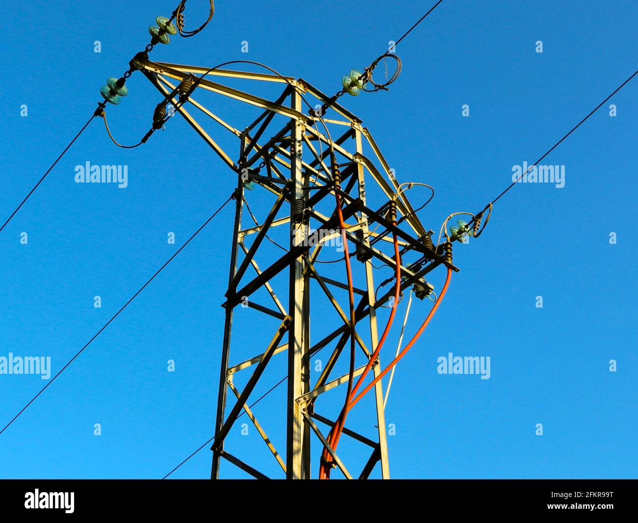 Electricity pylon with overhead cables in sunshine against a blue sky ...
