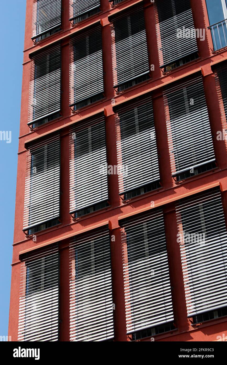 Close up of Red facade building with metal exterior screens on windows ...