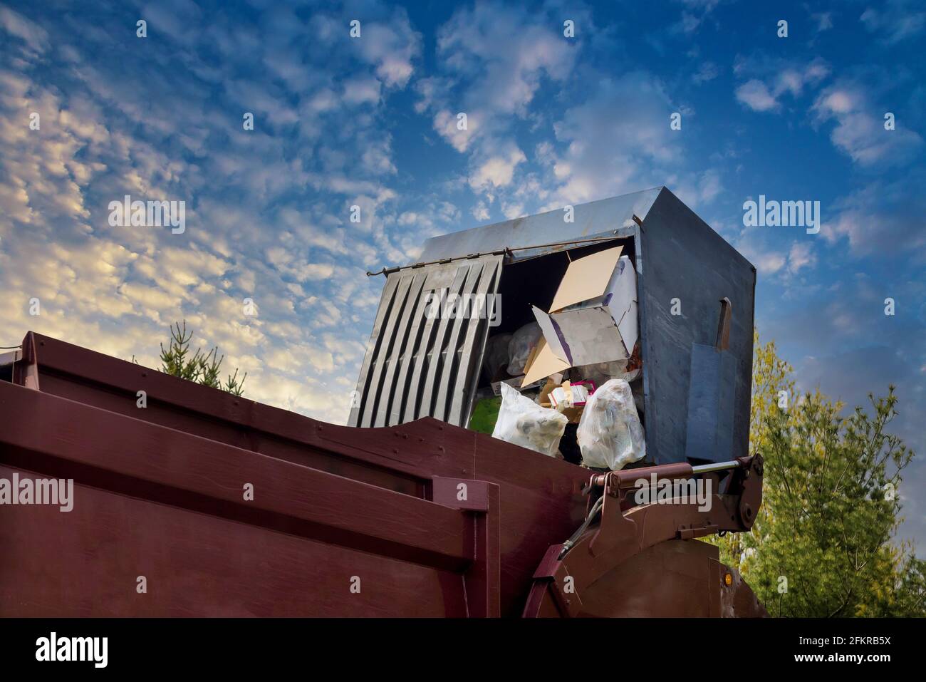 Lorry truck loading a skip waste management container on the street ...