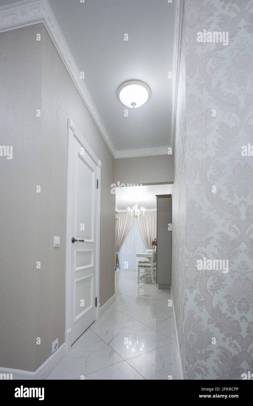 White hall with white wooden door, marble tiles floor and ceiling ...