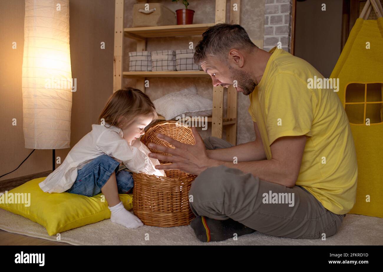 a happy father and his little daughter are surprised to open a wicker ...