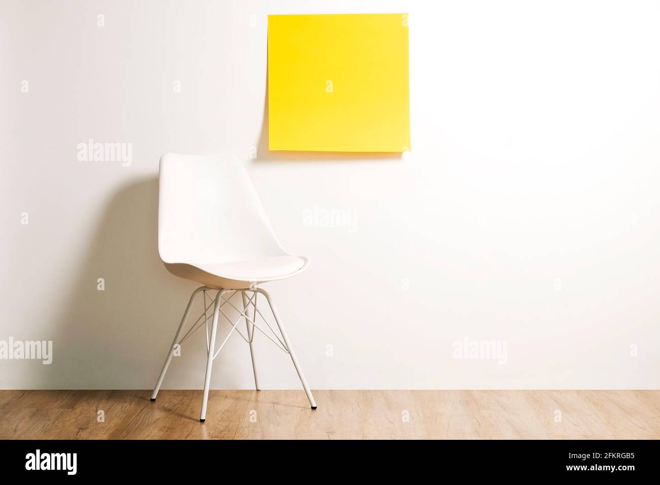 Single empty loft style chair on wooden floor with blank ad poster and ...