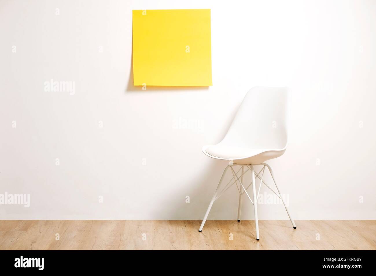 Single empty loft style chair on wooden floor with blank ad poster and ...