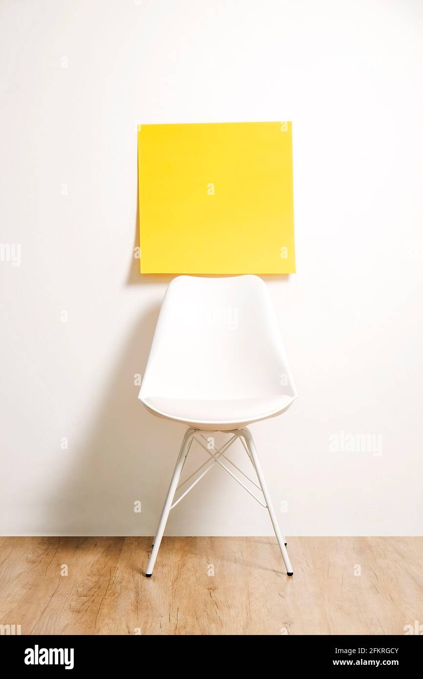 Single empty loft style chair on wooden floor with blank ad poster and ...