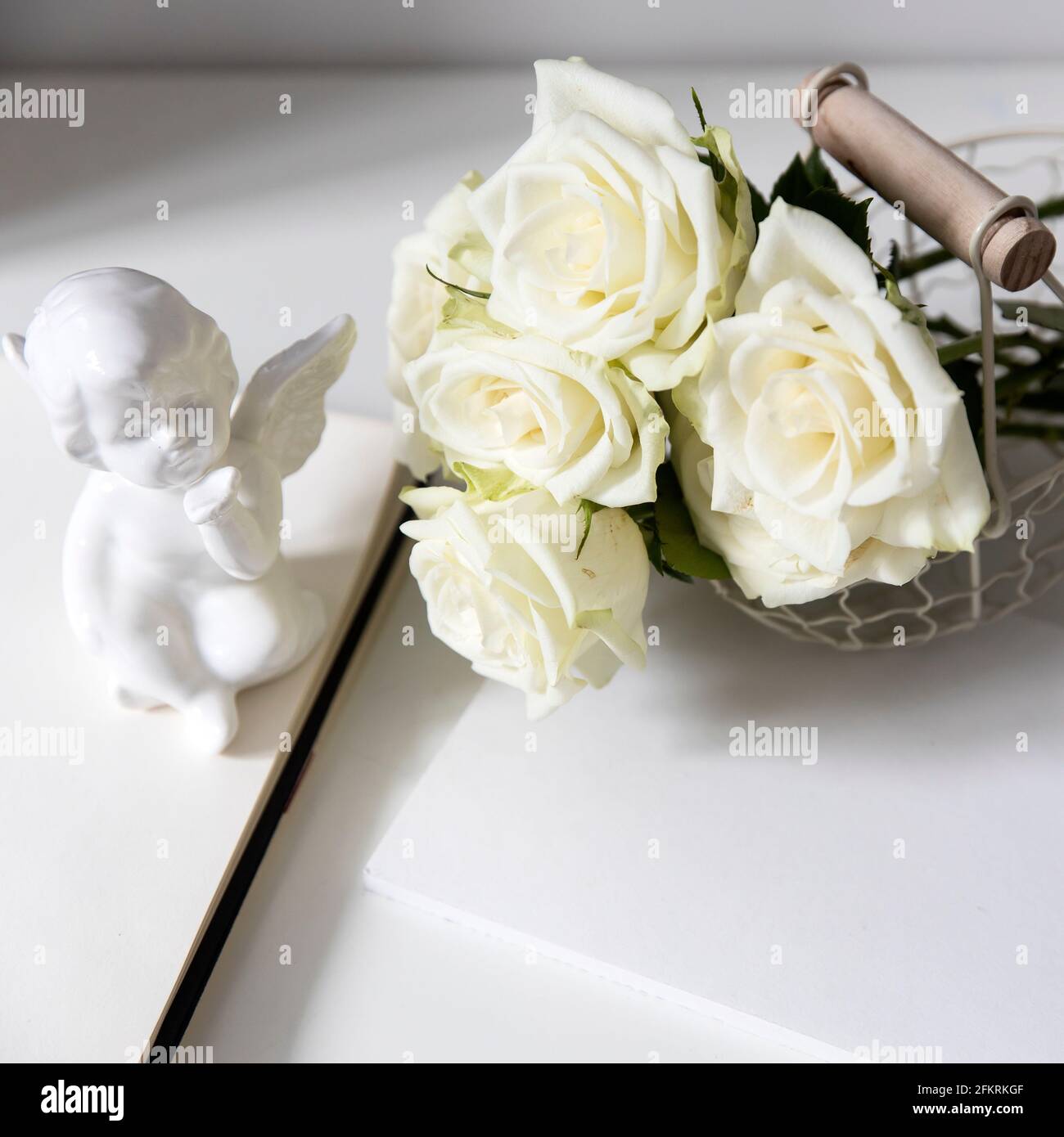 a white faience angel and three roses are on the table. Card Stock ...