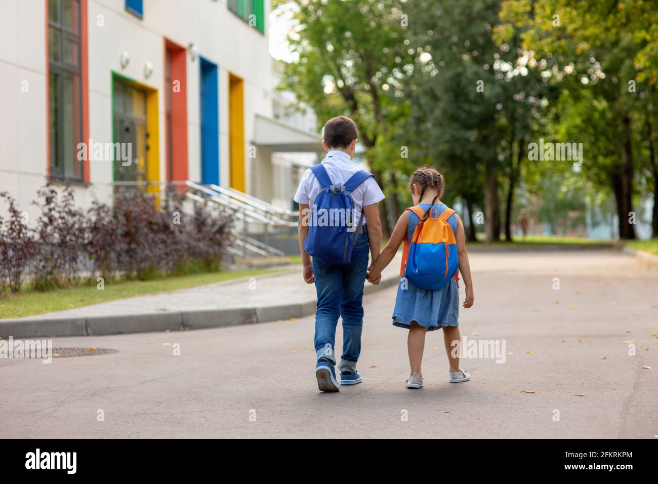 two schoolchildren, a little girl and a boy in a with backpacks go on ...