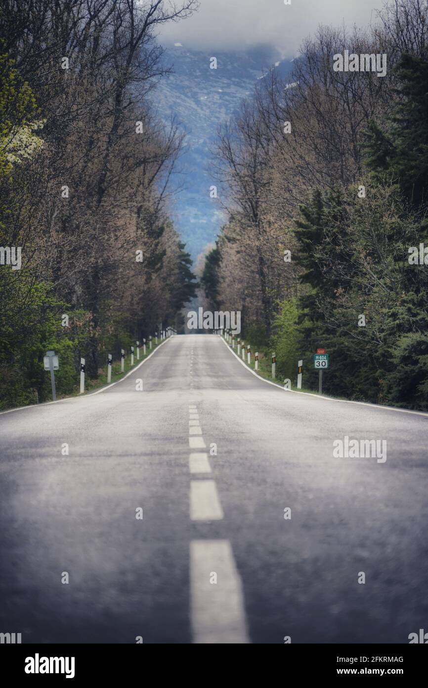 Vertical shot of an asphalt road with warning signs on a landscape ...