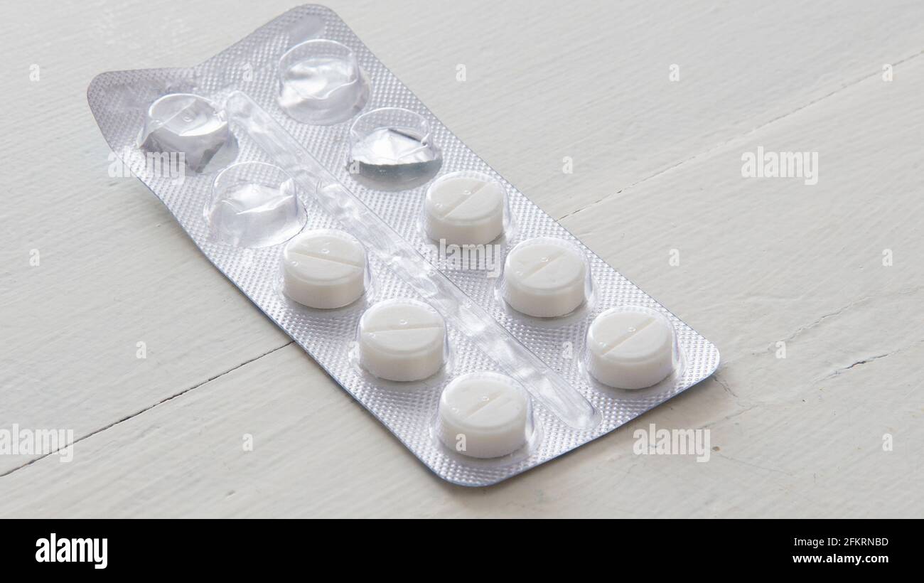 Close view of a plastic blister with white pills placed on top of a ...