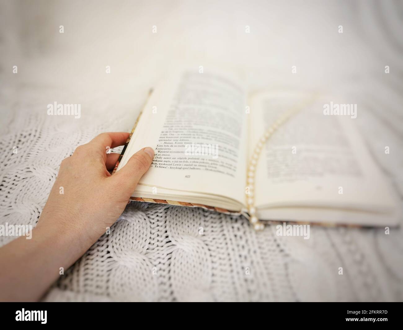 Person reading a book with white pearl beads on it Stock Photo - Alamy