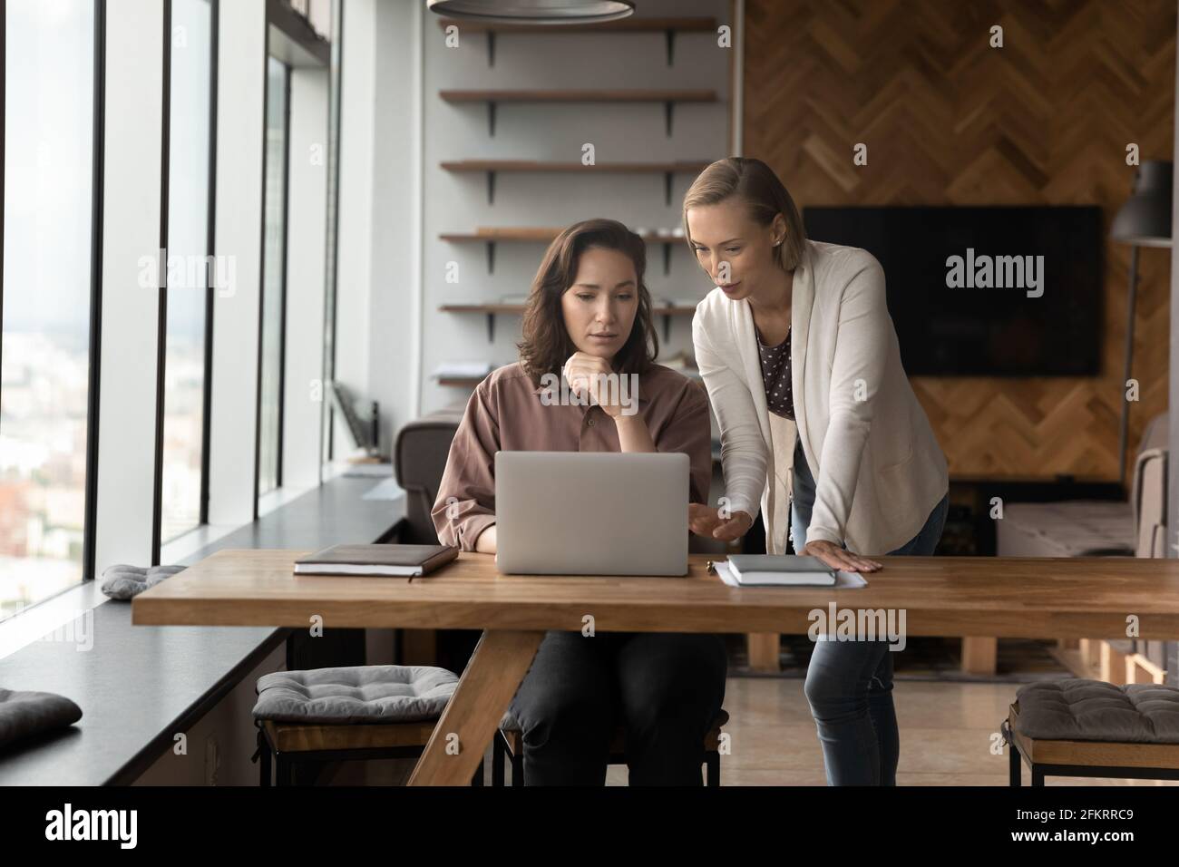 Female colleagues busy working on laptop at office meeting Stock Photo ...