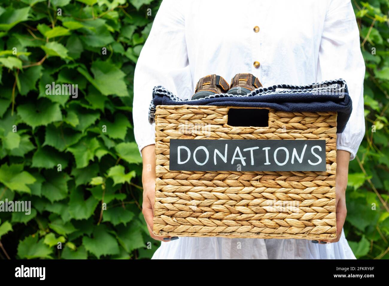 Female hands holding a box for clothing donations on a greenery ...