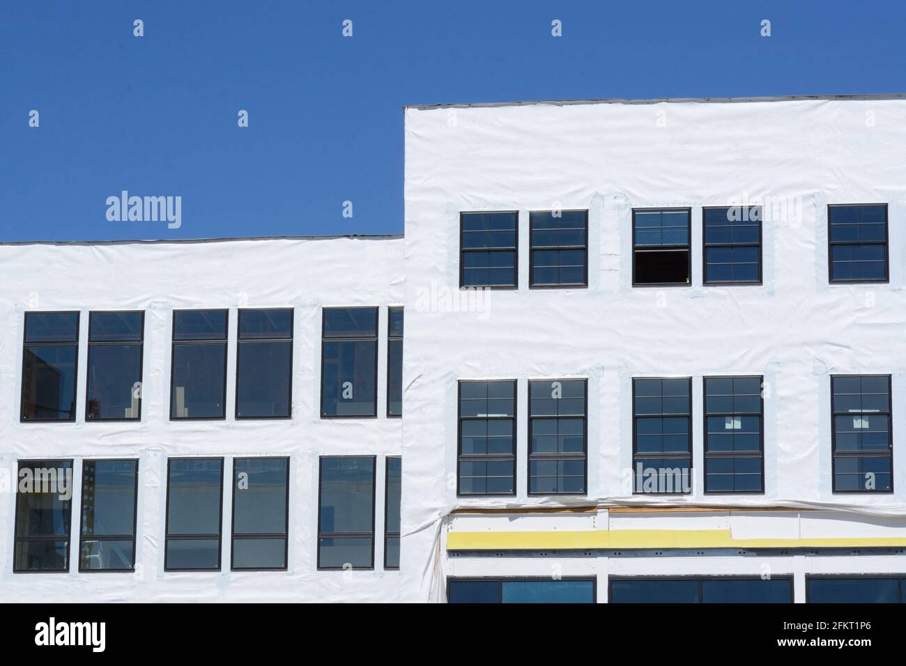 Construction of new building with windows and wrap still on exterior ...