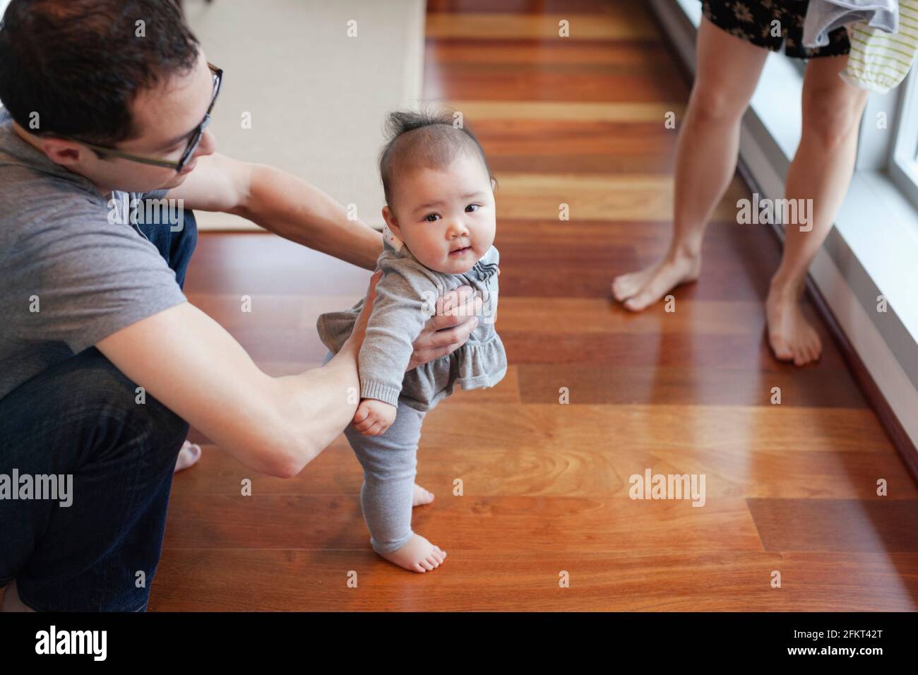 Father helping baby girl to stand Stock Photo - Alamy