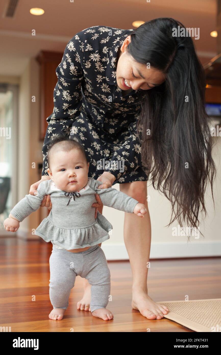 Mother helping baby girl to walk Stock Photo - Alamy