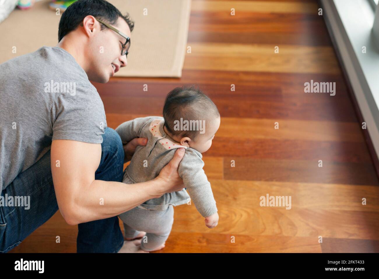 Father supporting baby girl to walk Stock Photo - Alamy