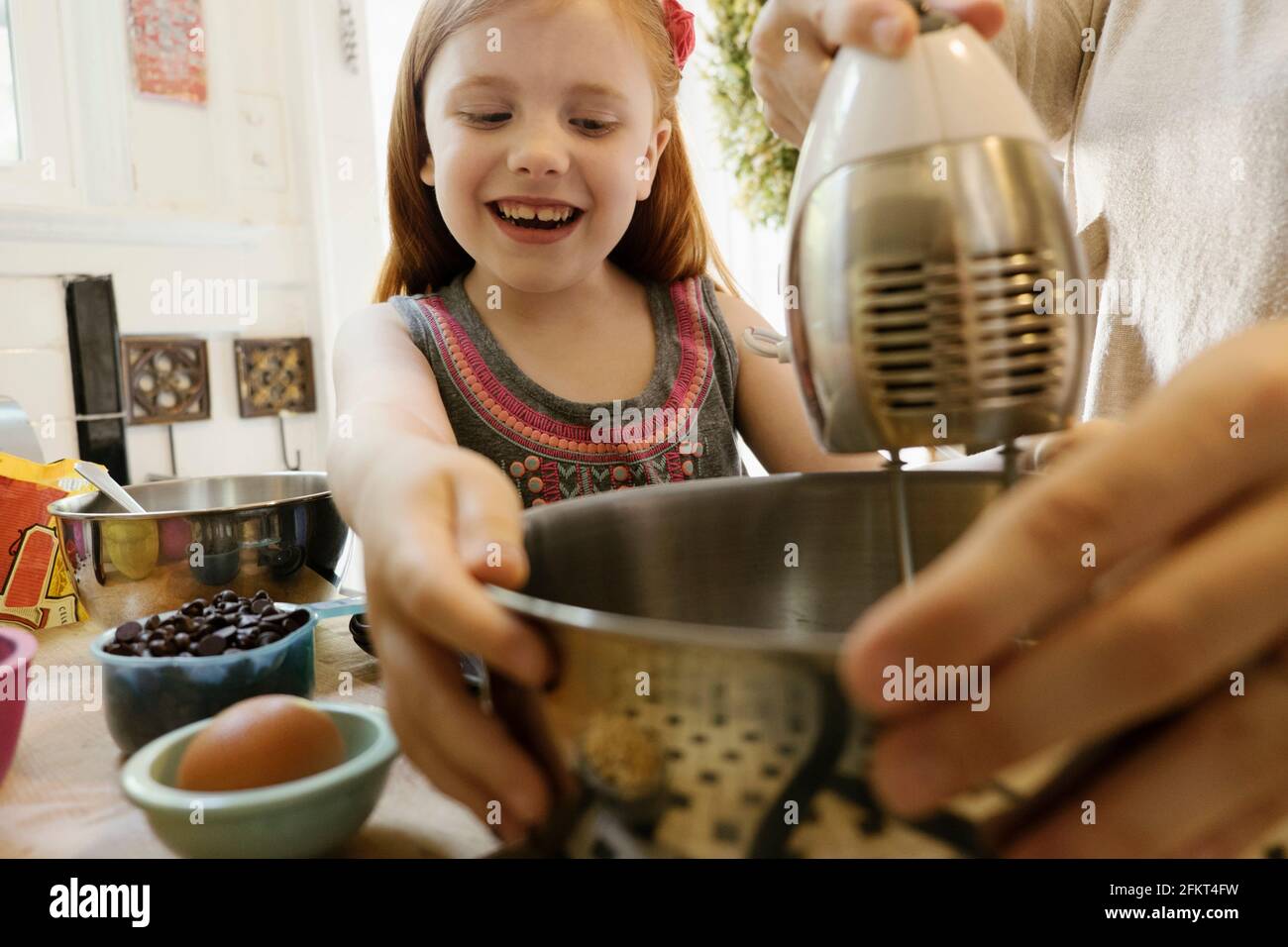 Girl giving mother a helping hand in kitchen Stock Photo - Alamy