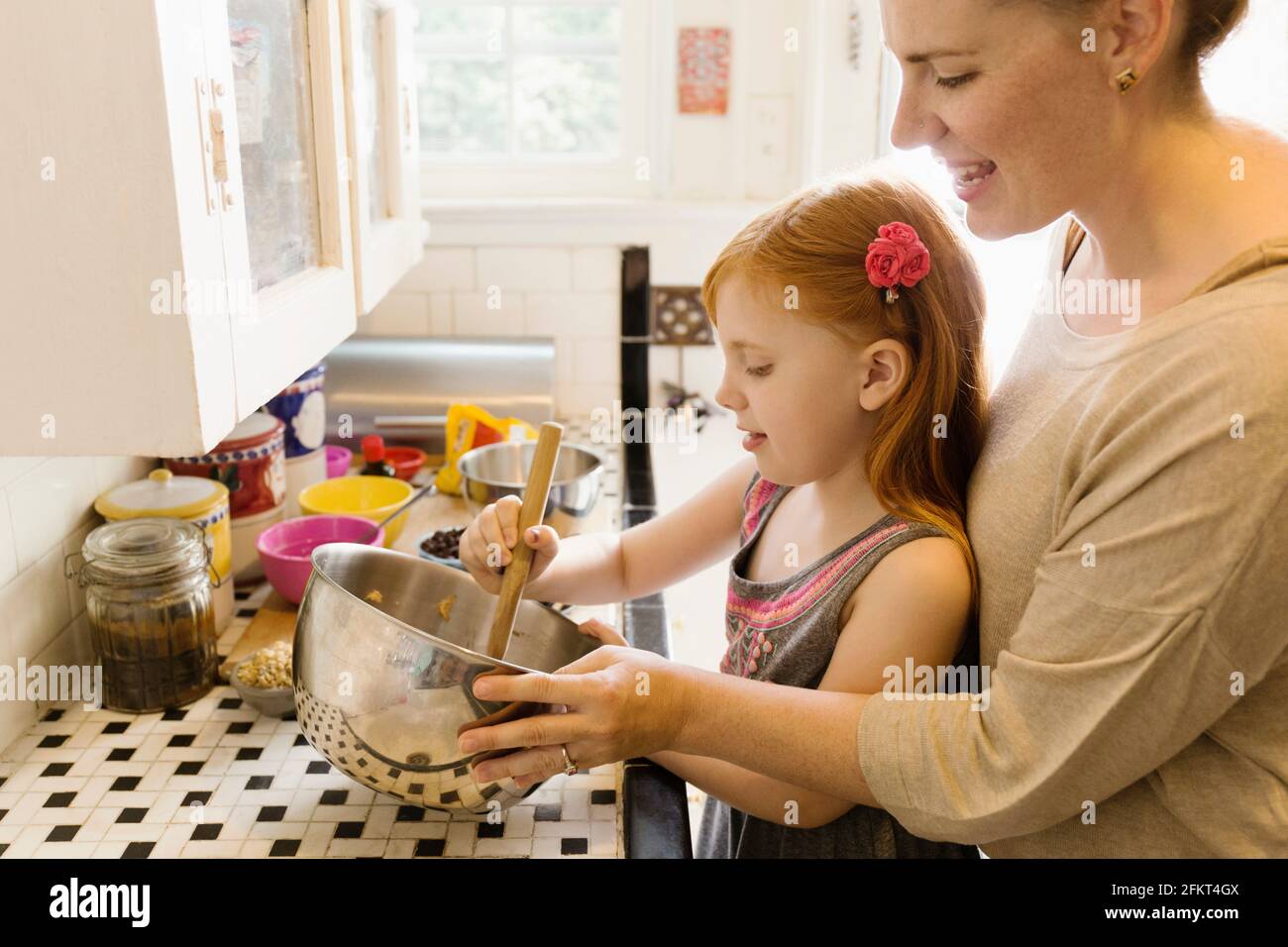 Girl and mother mixing ingredients in bowl in kitchen Stock Photo - Alamy