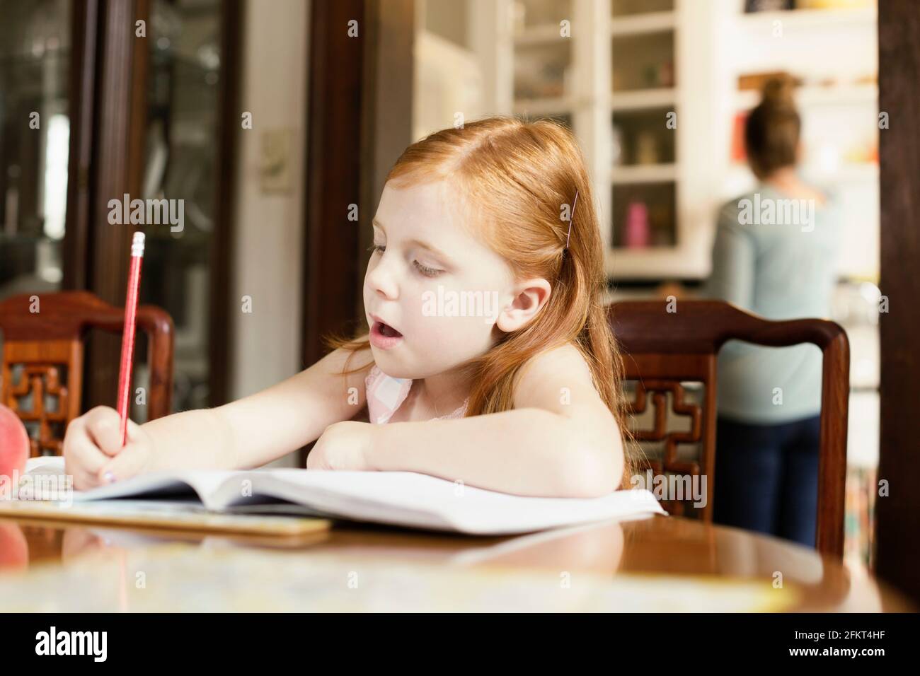 Girl doing homework at dining room table Stock Photo - Alamy