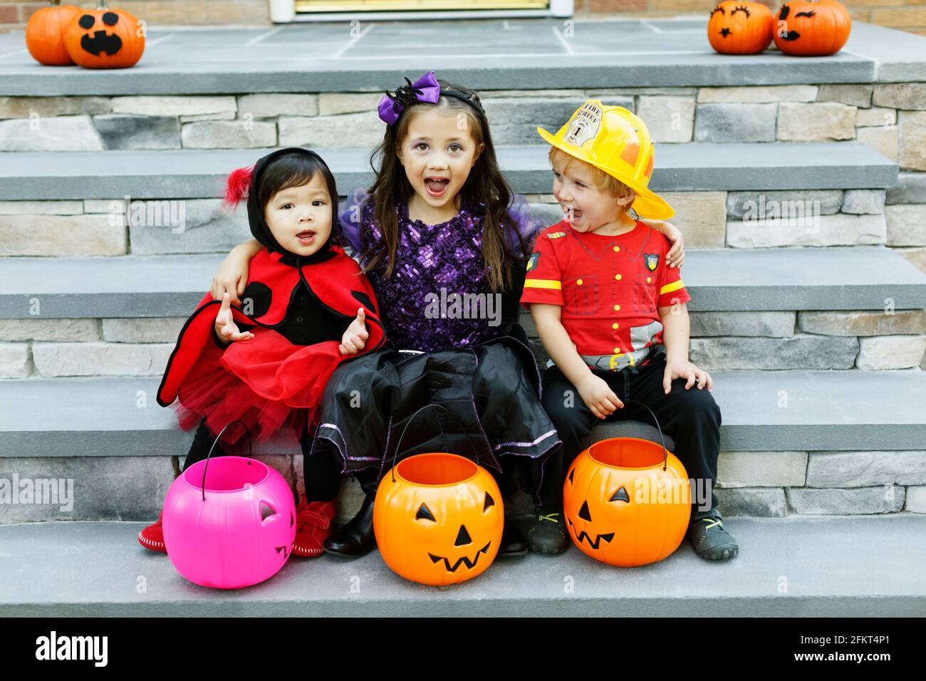 Three children sitting on steps with trick or treat buckets Stock Photo ...