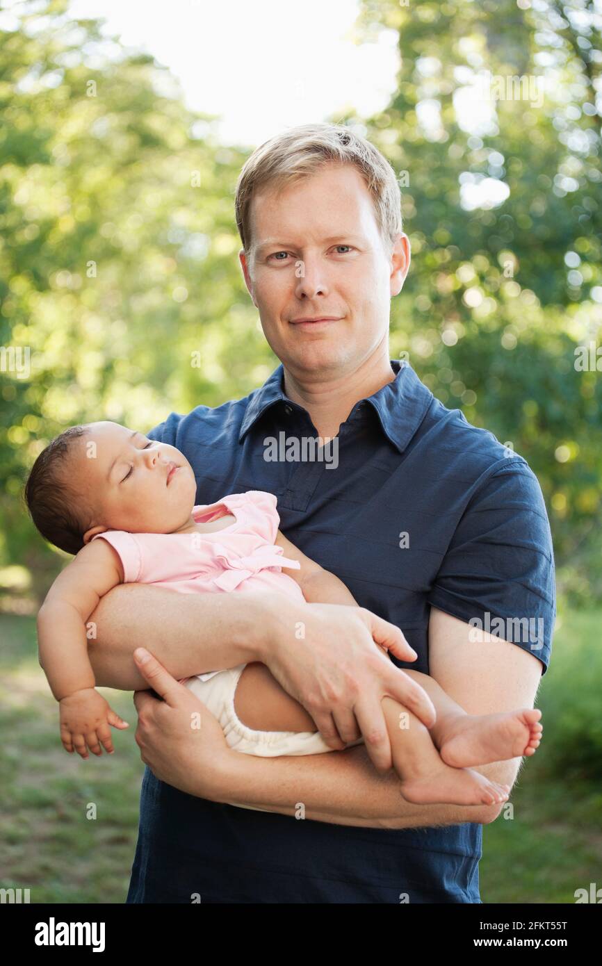 Father outdoors holding baby girl looking at camera smiling Stock Photo ...