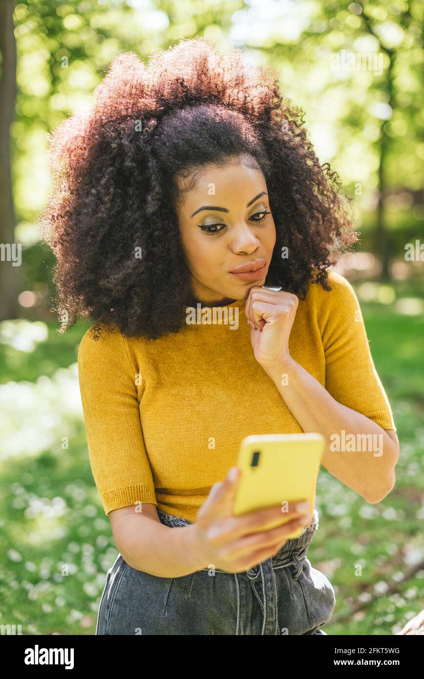 Pretty afro woman chatting in a garden, very surprised Stock Photo - Alamy