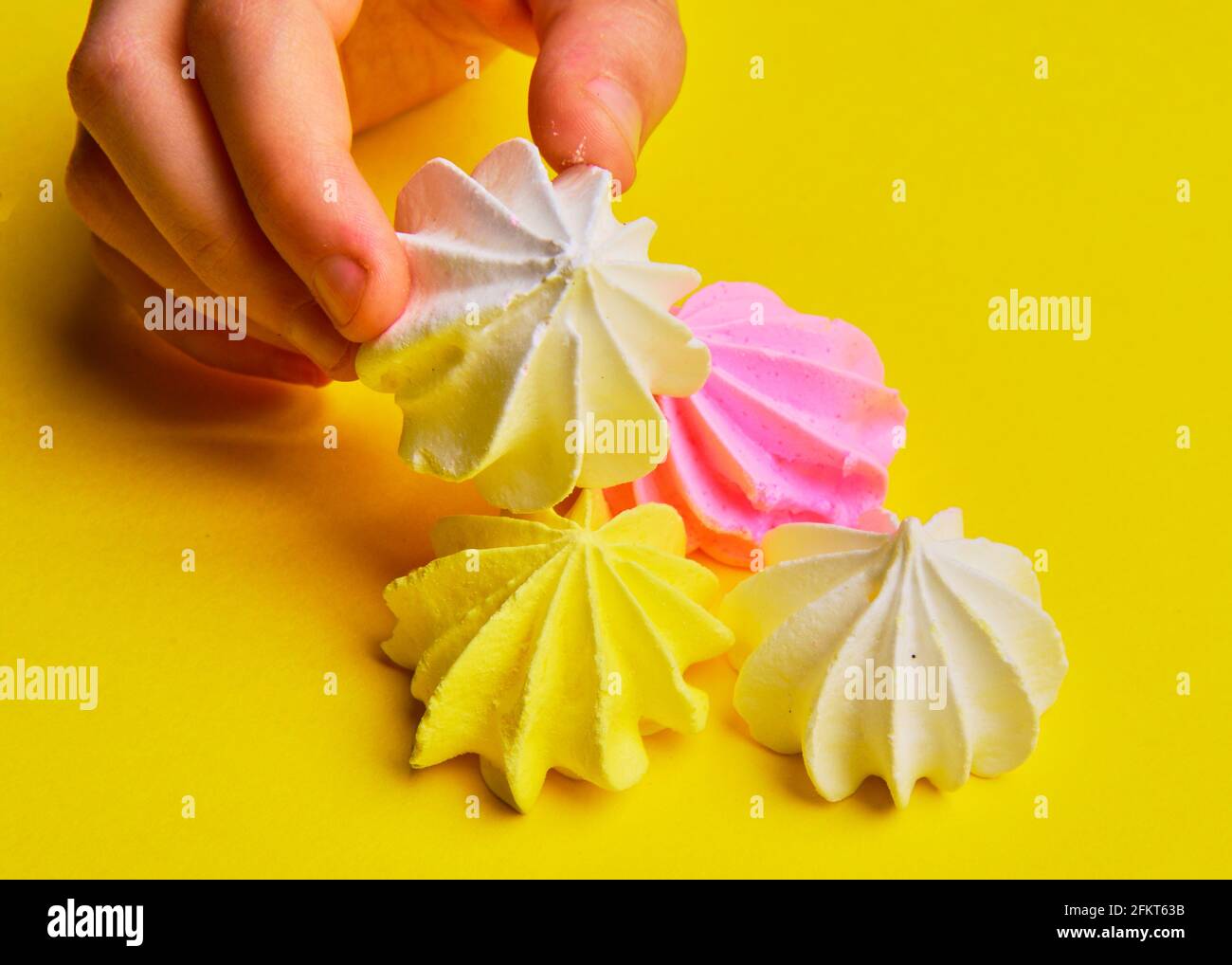 bright yellow background and colored meringues in hand Stock Photo - Alamy