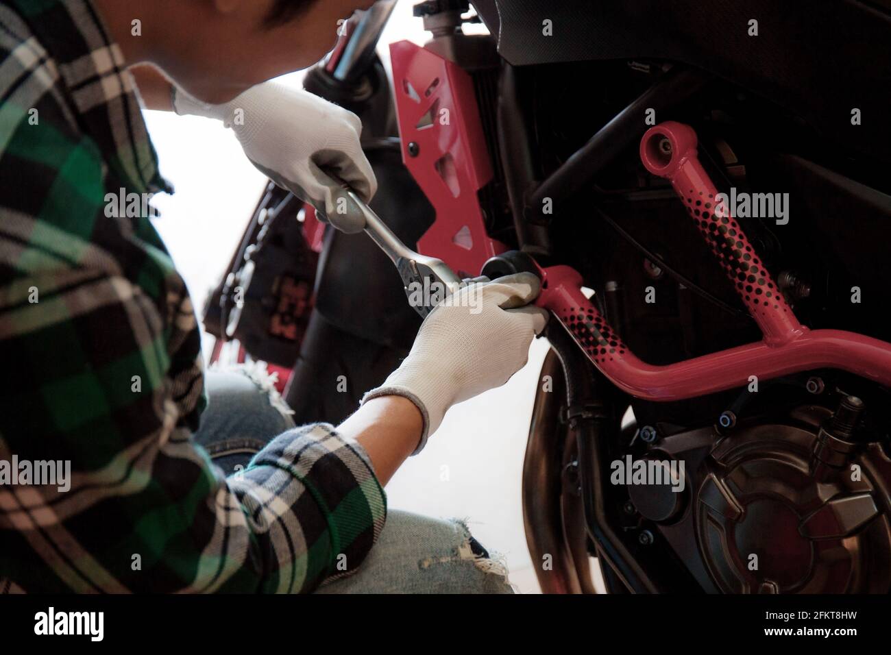 Young man fixing a motorcycle in the garage with background Stock Photo ...