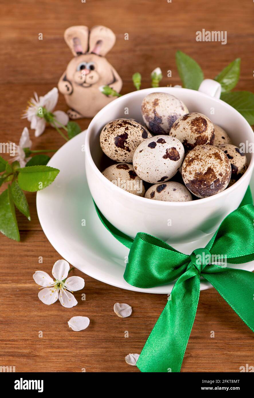 Easter background. Quail eggs in a white cup and a branch of blooming ...