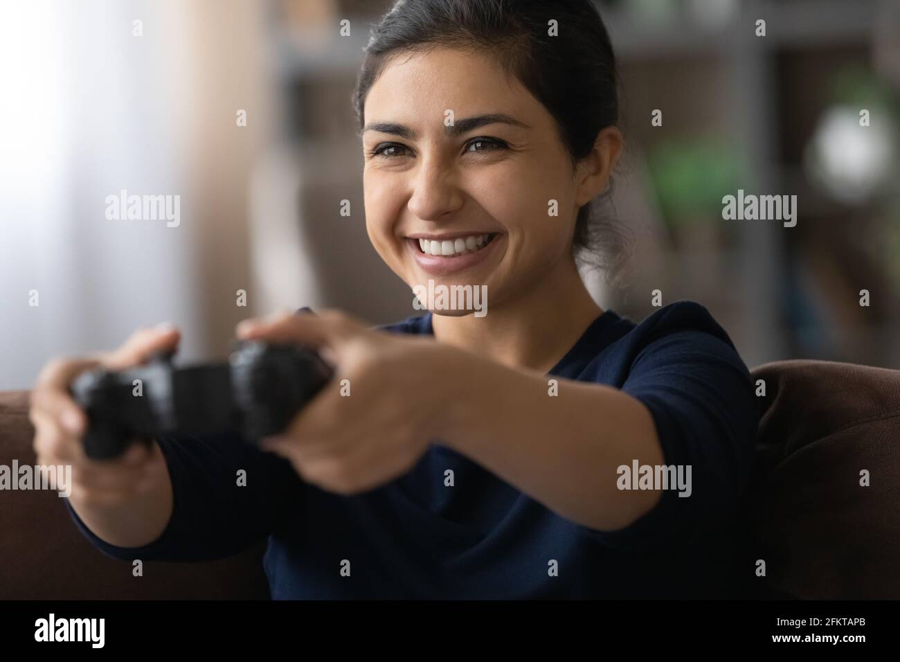 Close up happy Indian woman playing video game, holding controller ...