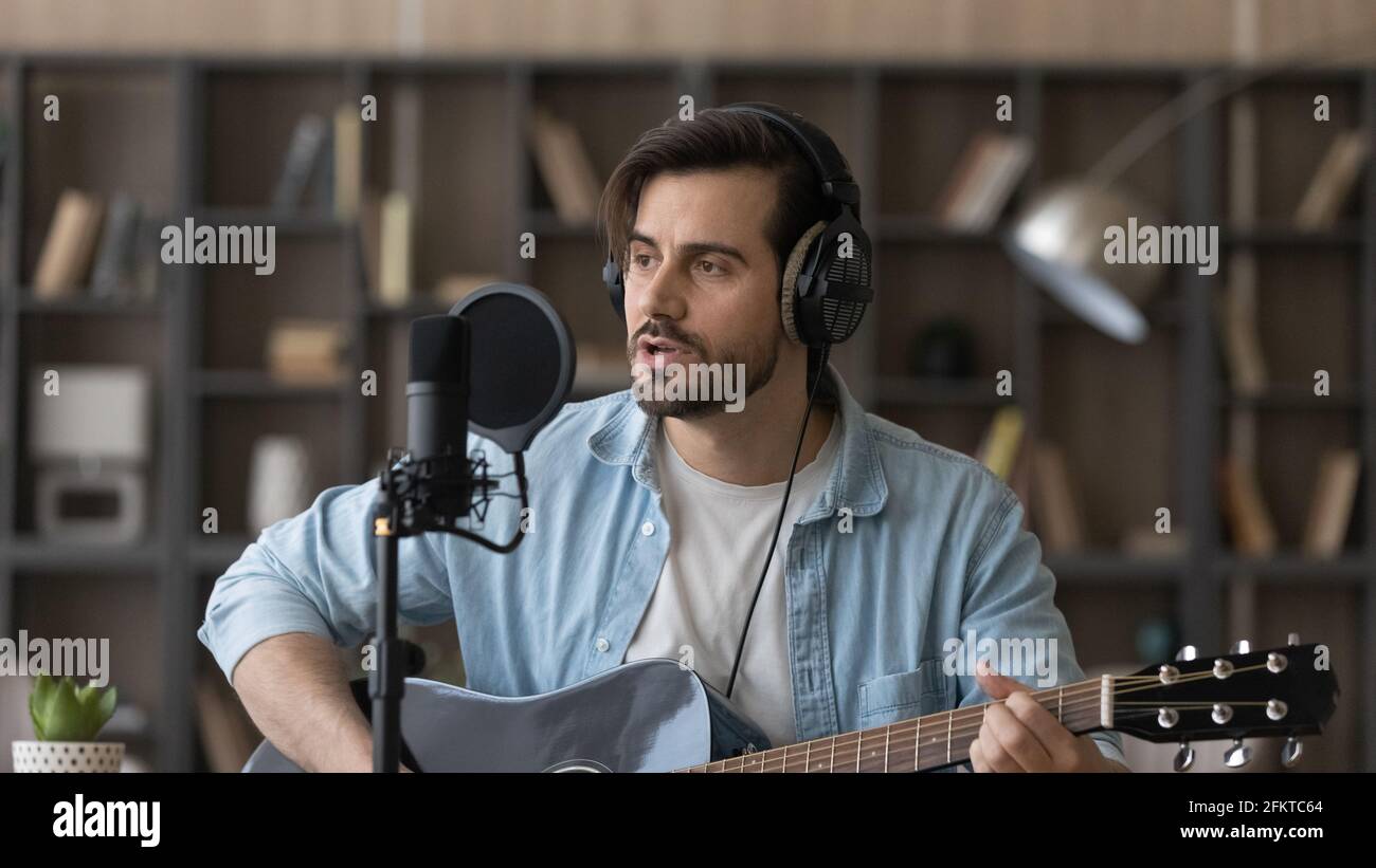 Close up man in headphones playing guitar, singing in microphone Stock ...