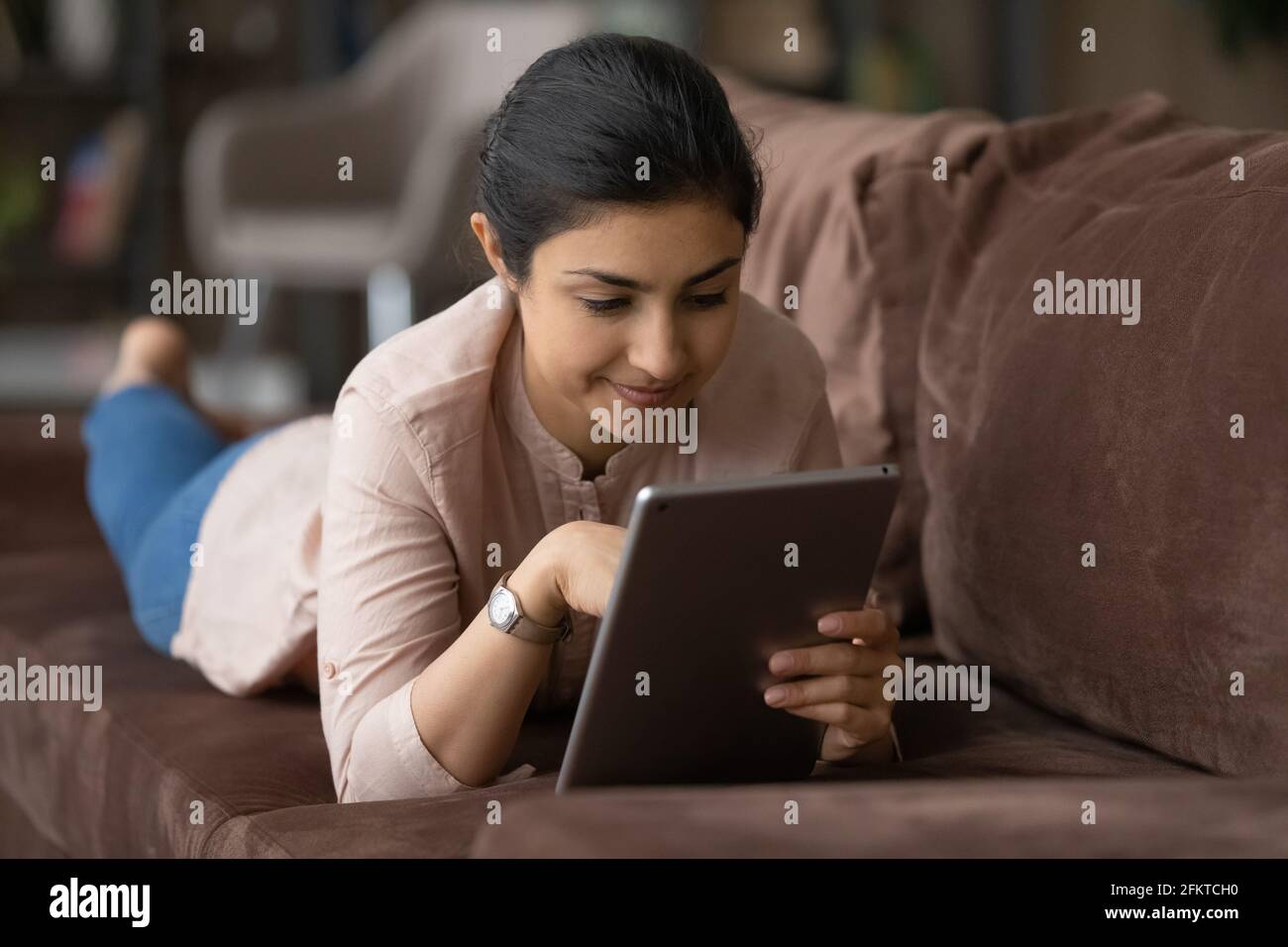 Close up Indian woman using tablet, lying on couch Stock Photo - Alamy