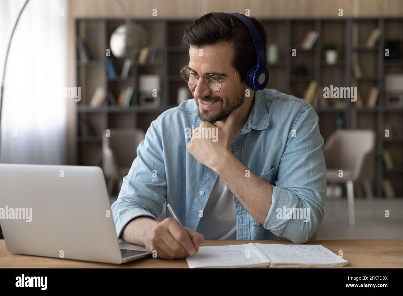 Close up smiling man in headphones using laptop, taking notes Stock ...