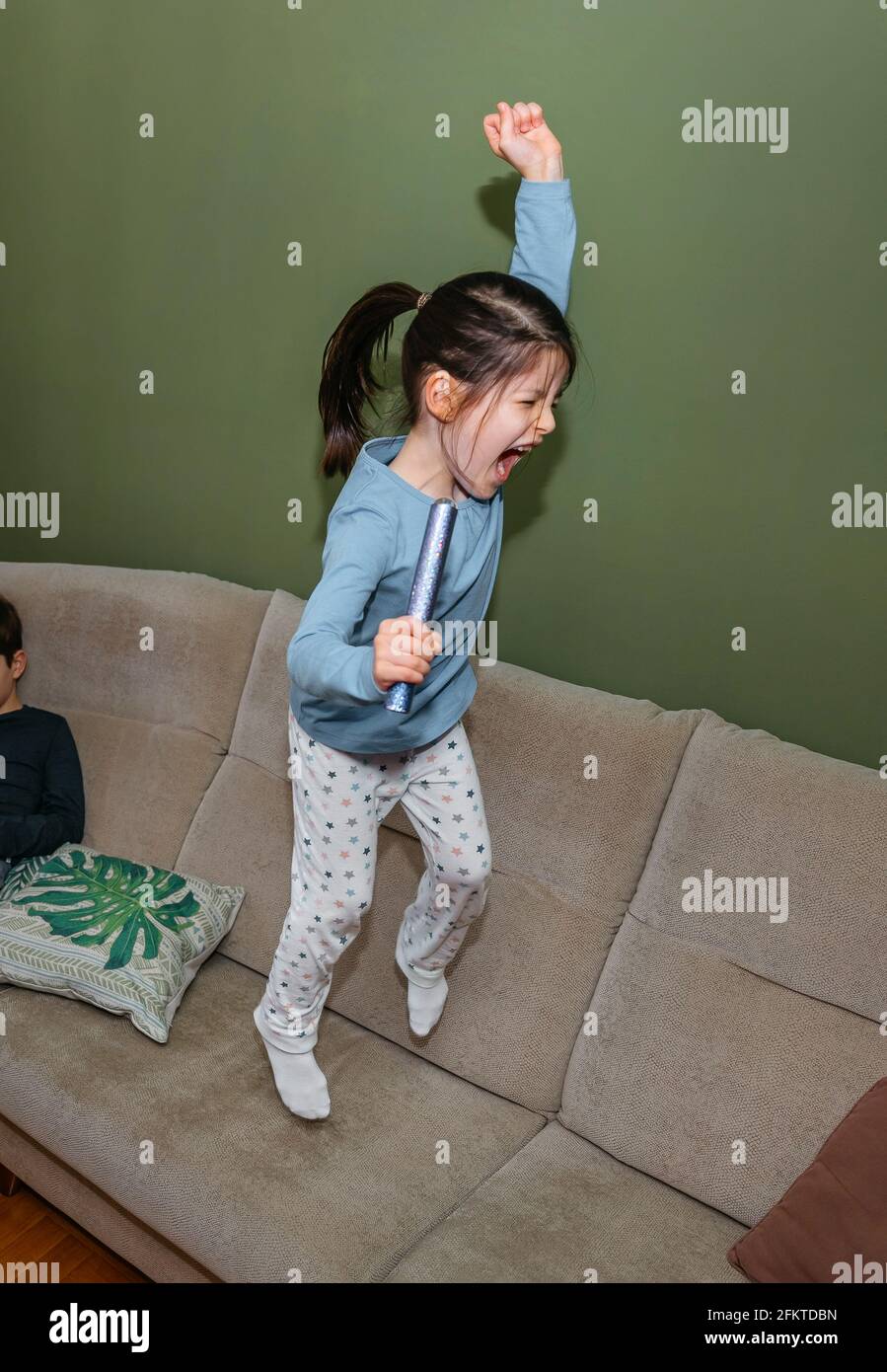 Girl jumping and playing on the sofa Stock Photo - Alamy