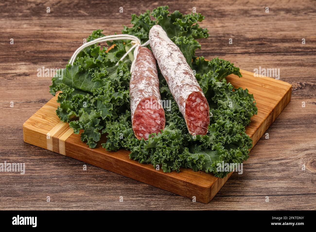 Spanish Fuet sausage with salad leaves over wooden background Stock ...
