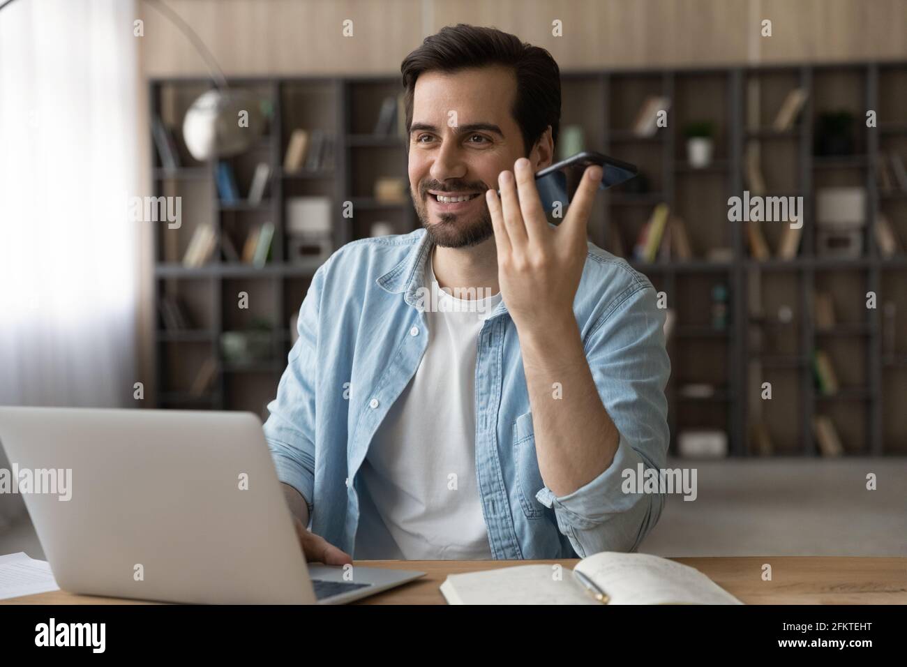 Smiling businessman recording audio voice message on smartphone ...