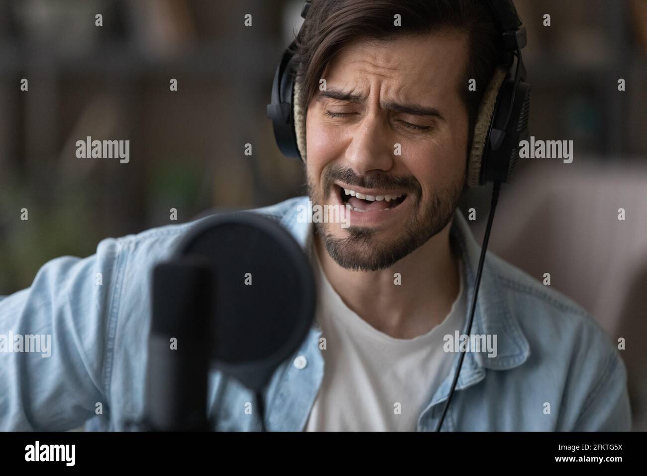 Close up man singer in headphones singing, using professional ...